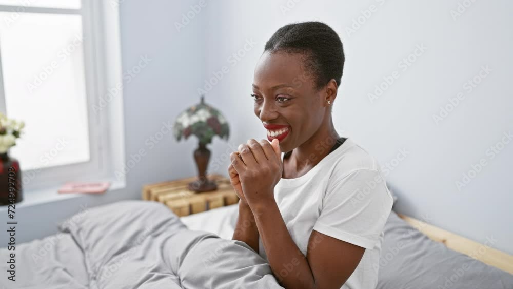Excited african american woman lying in bed at home, laughing giddily ...