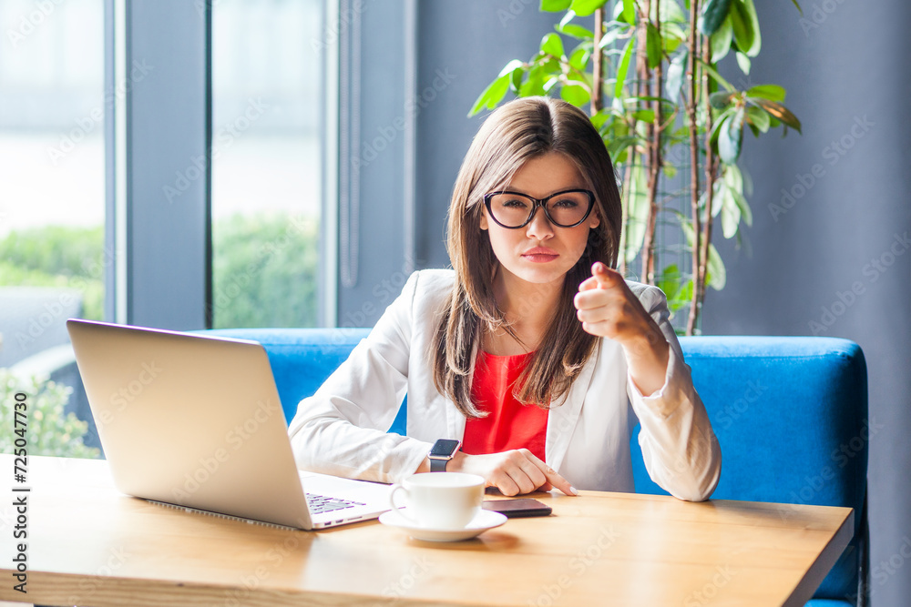 Portrait of strict bossy woman working on laptop looking at camera ...