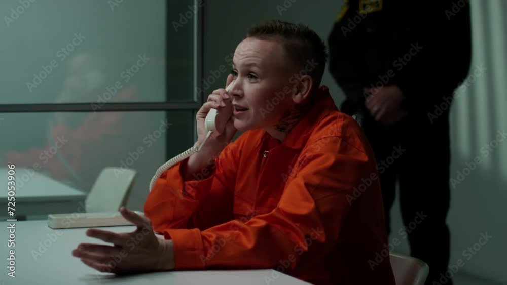 Nervous female prisoner in orange jail uniform sitting in meeting room ...