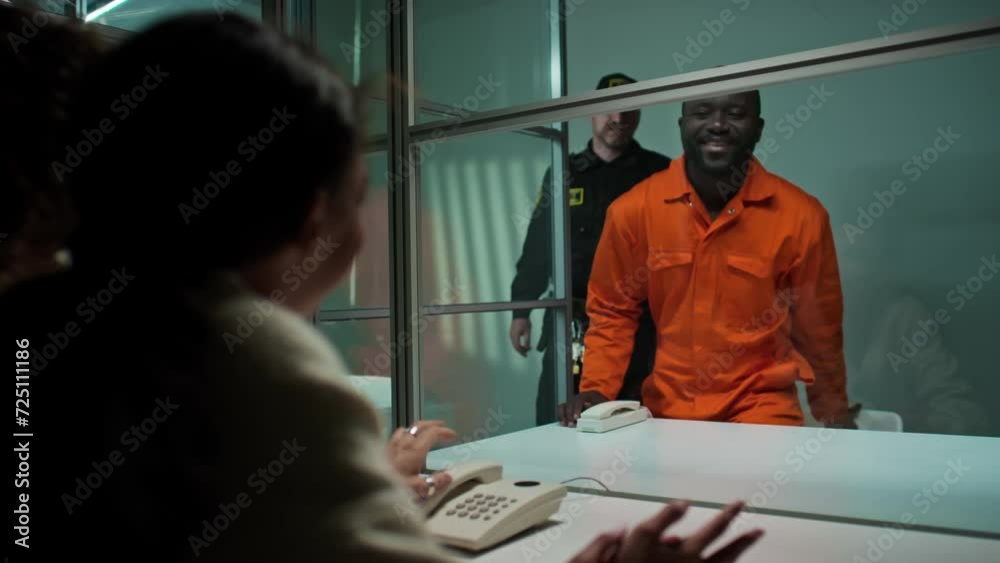 African American inmate walking into visiting room, sitting behind ...