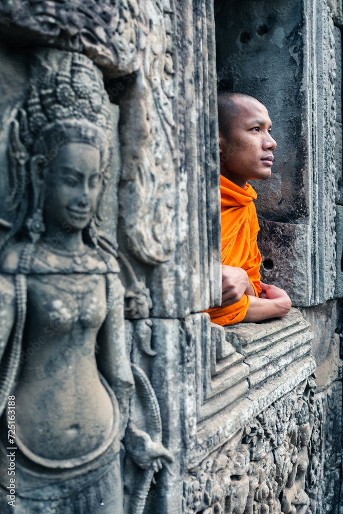 Monk leaning out of window at the temple with stone carvings, Angkor ...