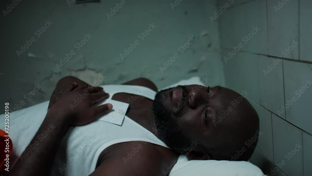 Sad African American inmate lying on bed, watching photo of beloved ...