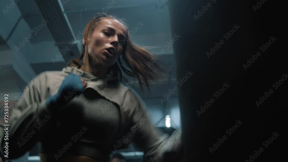Close up of female kickboxer in boxing bandages hitting punching bag in ...
