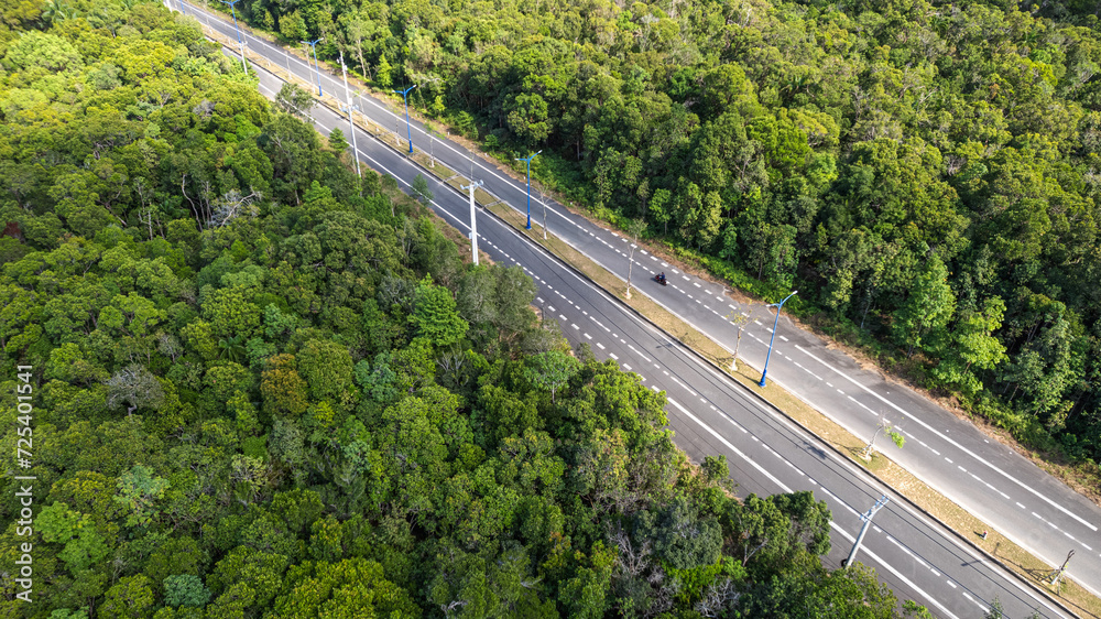 Aerial view of a multi-lane highway cutting through a dense forest with ...