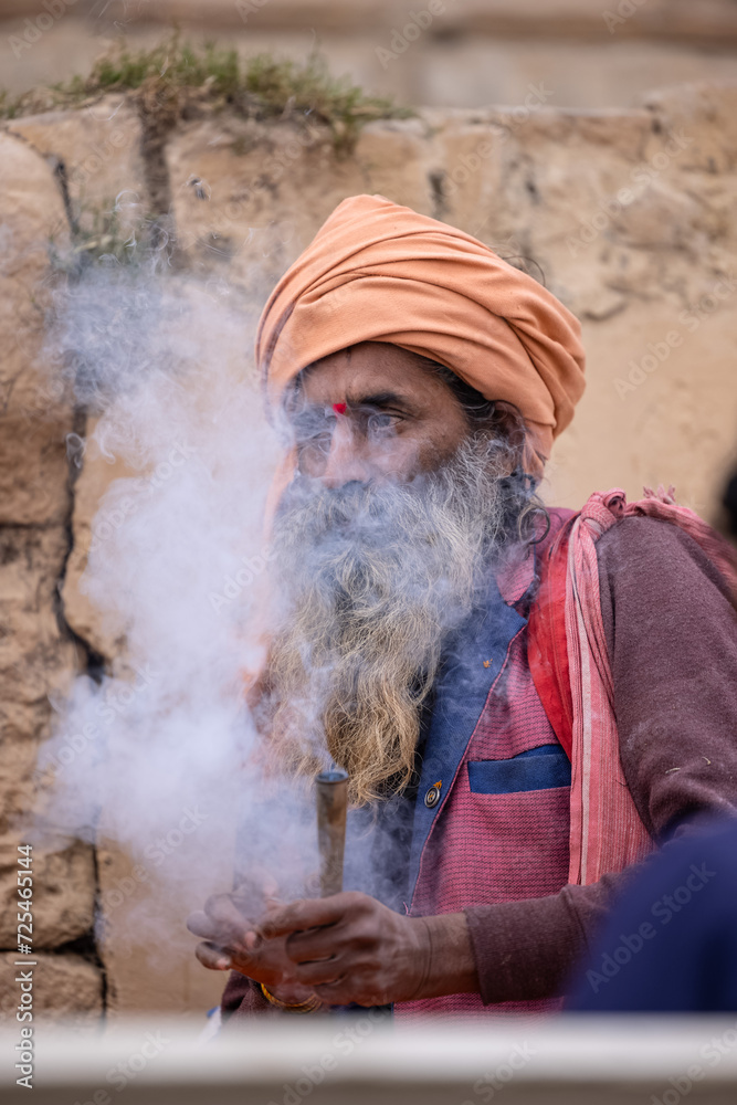 Indian holy old sadhu smoking during the kumbh fair during winter day ...