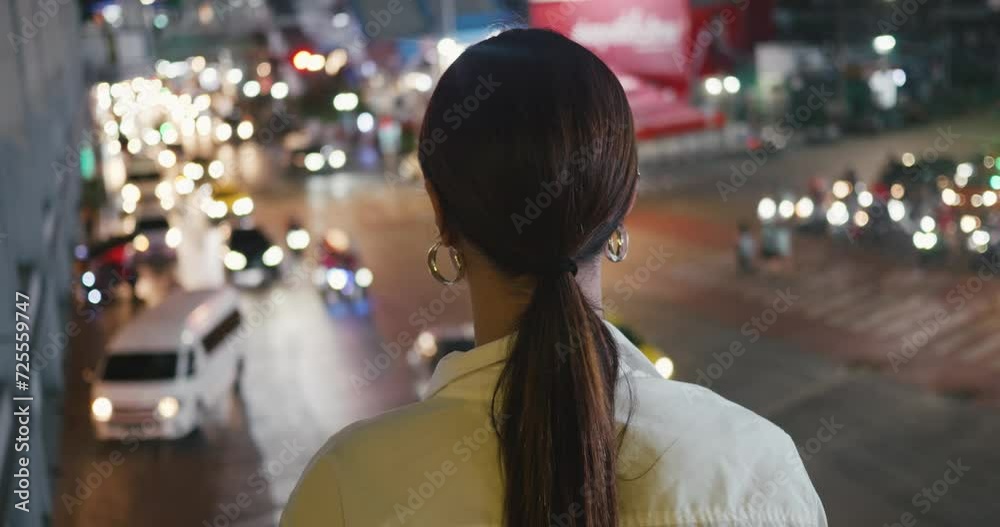 In evening woman gazes at bustling city traffic crowdedness back view ...