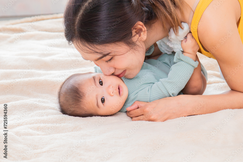 Selective focus of Asian young mother kissing baby on bed, Beautiful woman hugging toddler ...