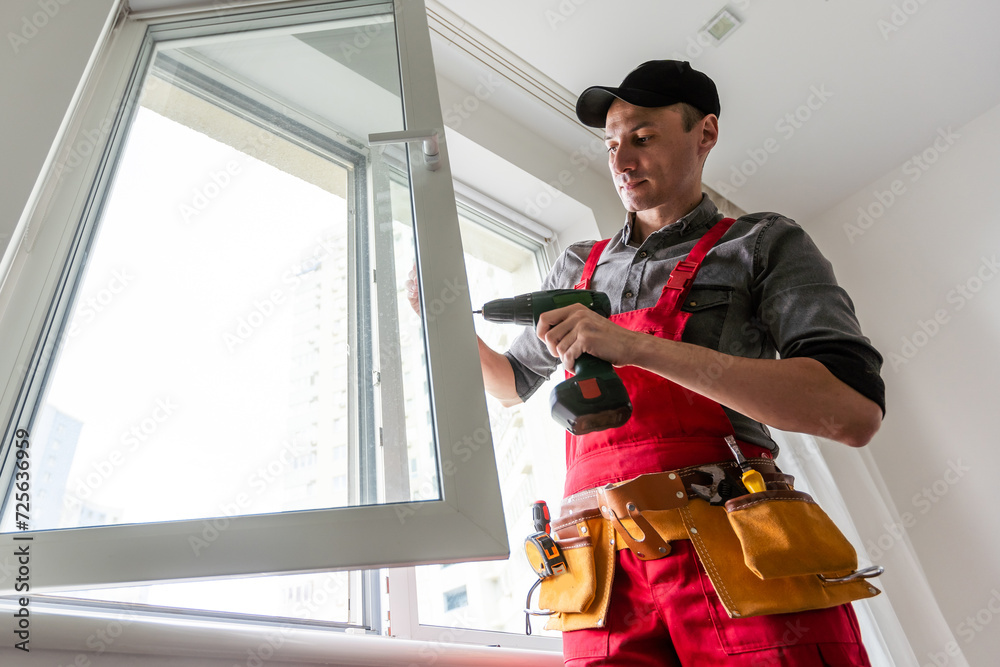 Professional installer of plastic windows poses in a working uniform ...