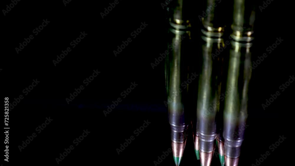 Rifle bullets rotate and cast their reflection on the glass table with ...
