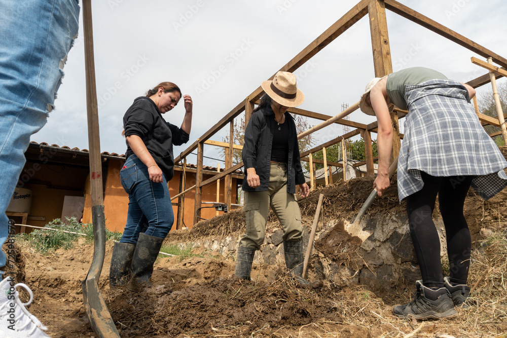 Women volunteers, their hands laden with mud, building an earth wall ...
