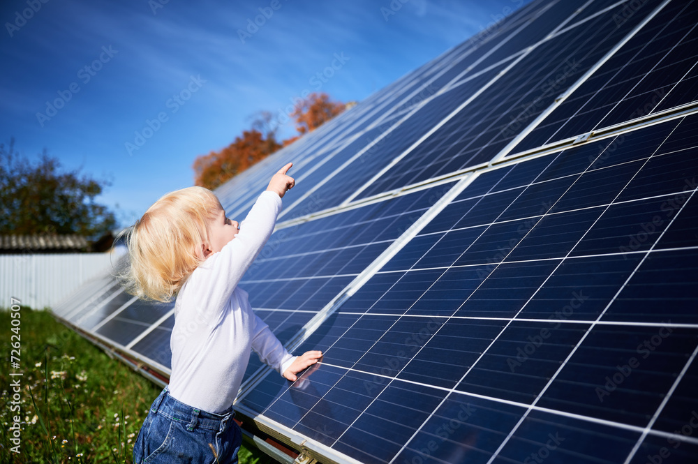 Little child looking at big solar panels. Interested boy investigates ...