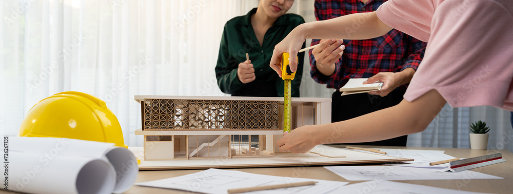 Smart architect engineer and interior designer working together and measuring house model by ...