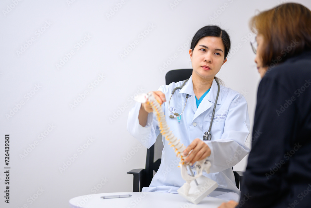 Aging and back pain concept: Female orthopedic doctor shows her senior ...