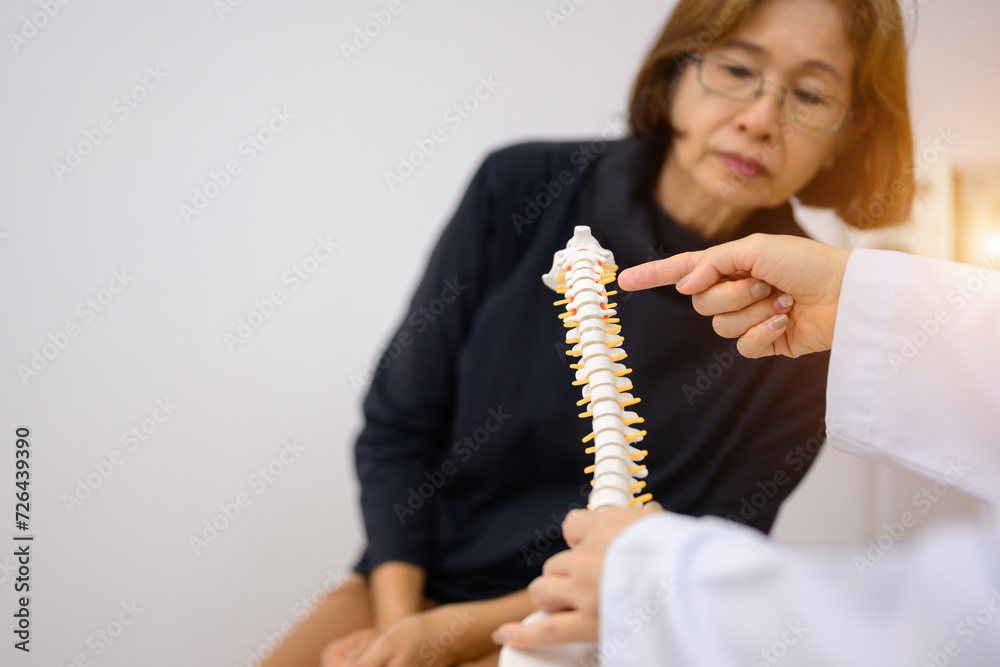 Aging and back pain concept: Female orthopedic doctor shows her senior ...