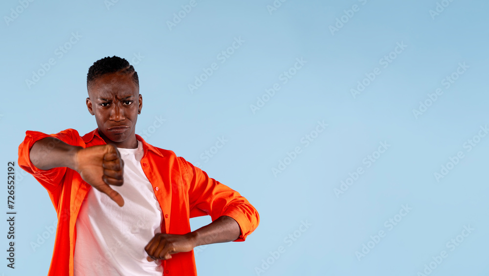 woman in orange shirt giving thumb down gesture, dislikes something ...