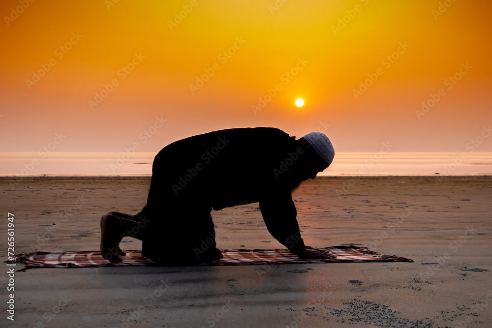 Asian Muslim man praying under the open sky by the sea at sunset ...