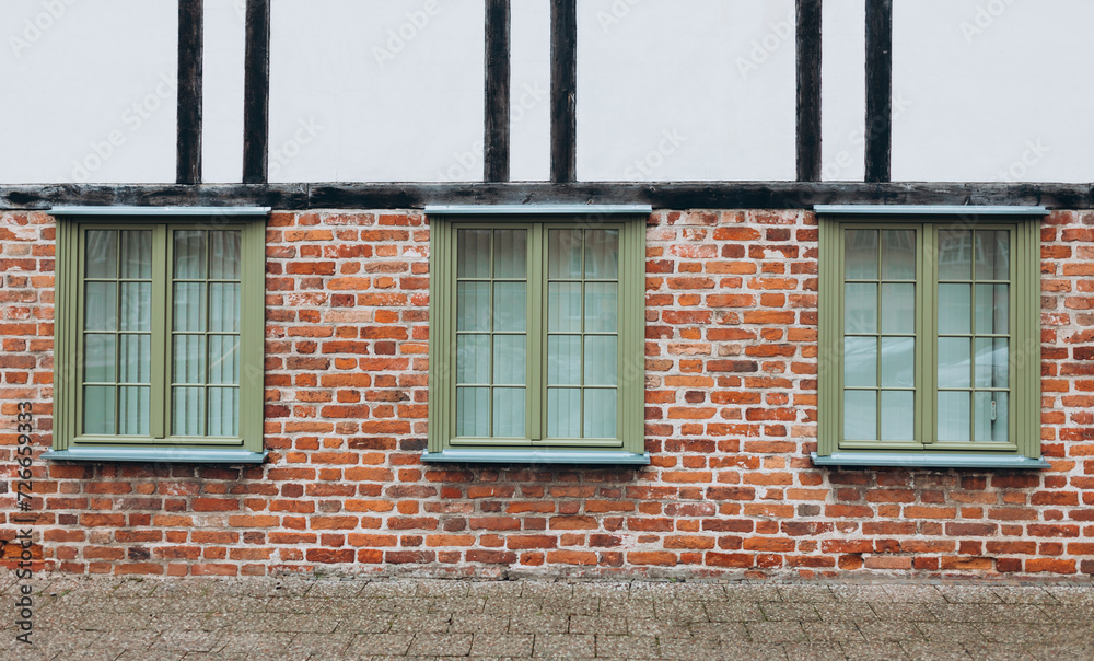 The facade of a brick house with identical square windows. Brick wall ...