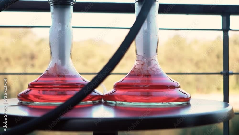 Beautiful red hookah flasks stand on the pier on the river bank ...