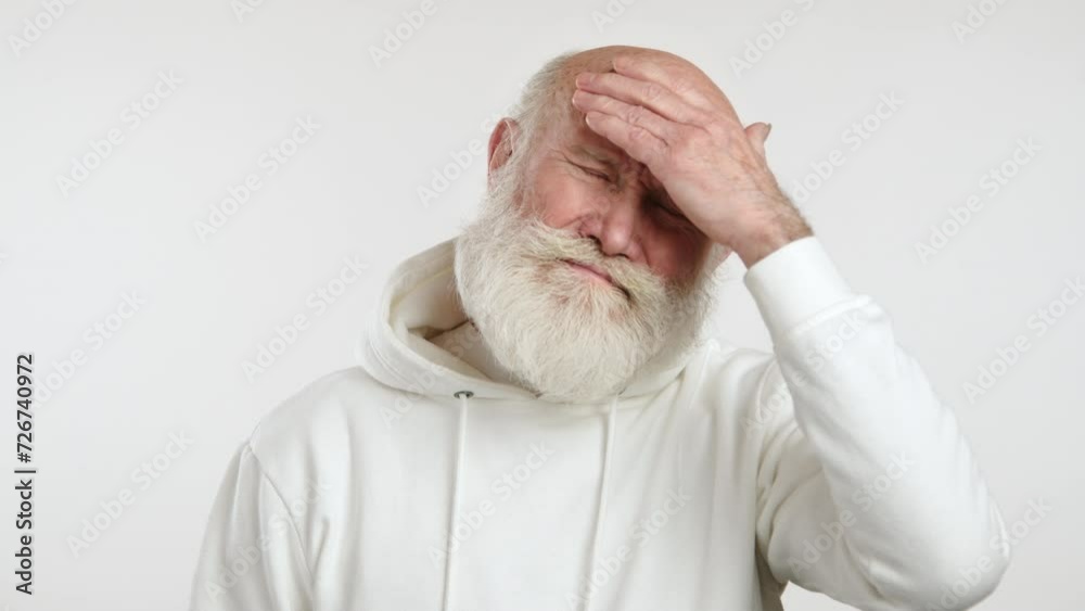 A video of an elderly man in a white hoodie touching his forehead and ...
