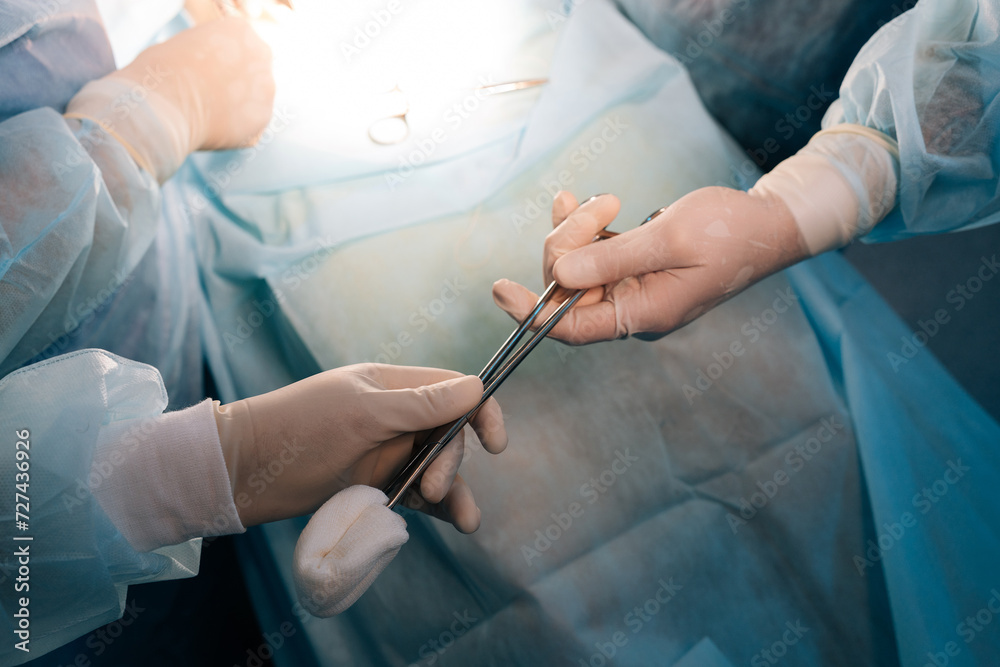 Top view of unrecognizable female nurse assists male surgeons, giving ...
