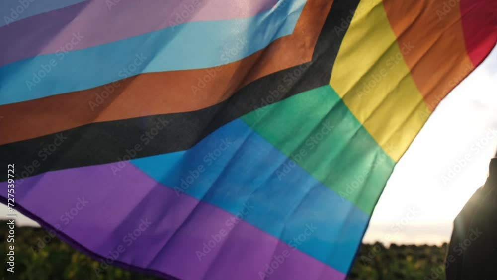 Rainbow LGBTQIA flag waving in wind made from silk material on field ...