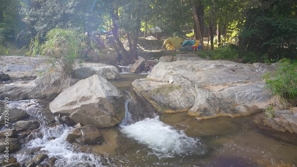 Backlit nature water flow stream waterfall with camping tent and family ...