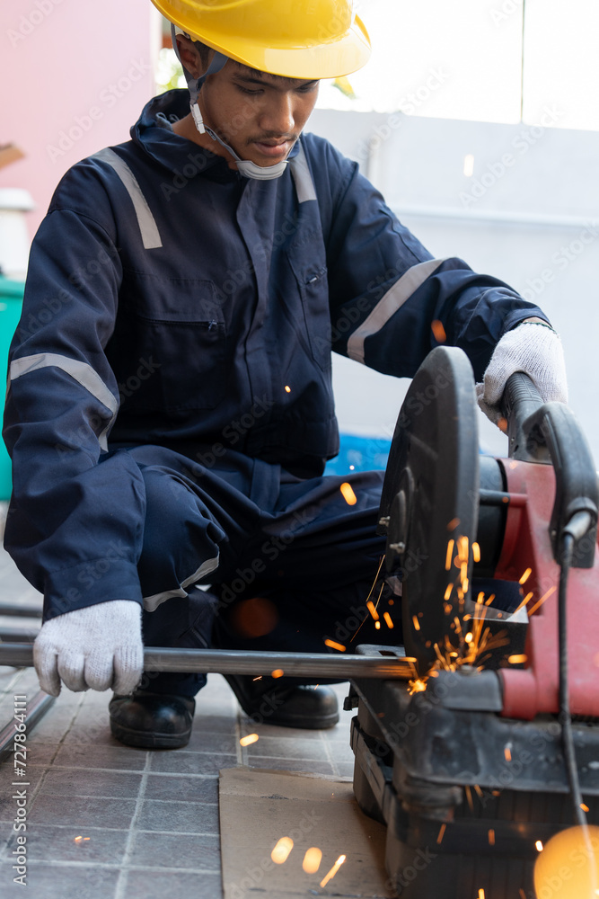 Asian worker wearing a safety suit uses a steel cutting (circular saw ...