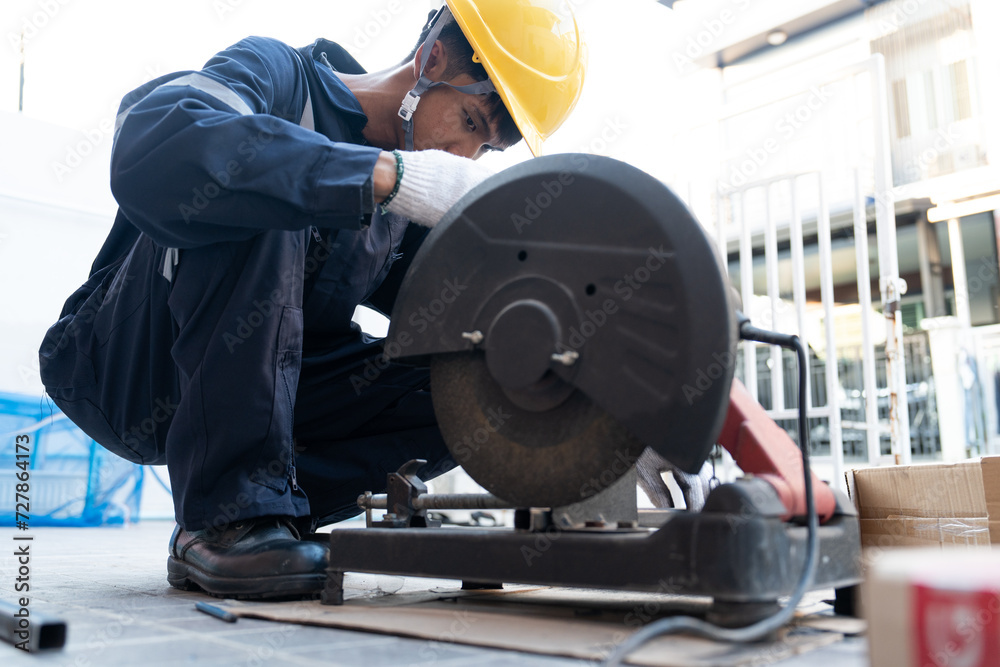 Asian worker wearing a safety suit uses a steel cutting (circular saw ...