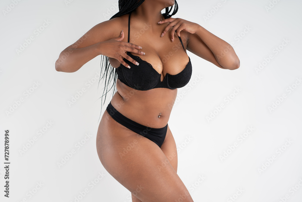 Curvy busty plus size model in push up bra on gray background, overweight African black woman in ...