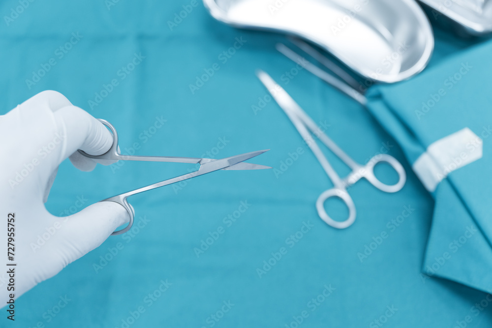 Surgeon doctor's hand with hygiene glove taking scissor surgical set ...