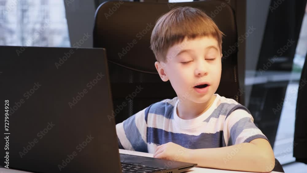 6 year child typing on the laptop. The teacher man goes to pupil looks ...