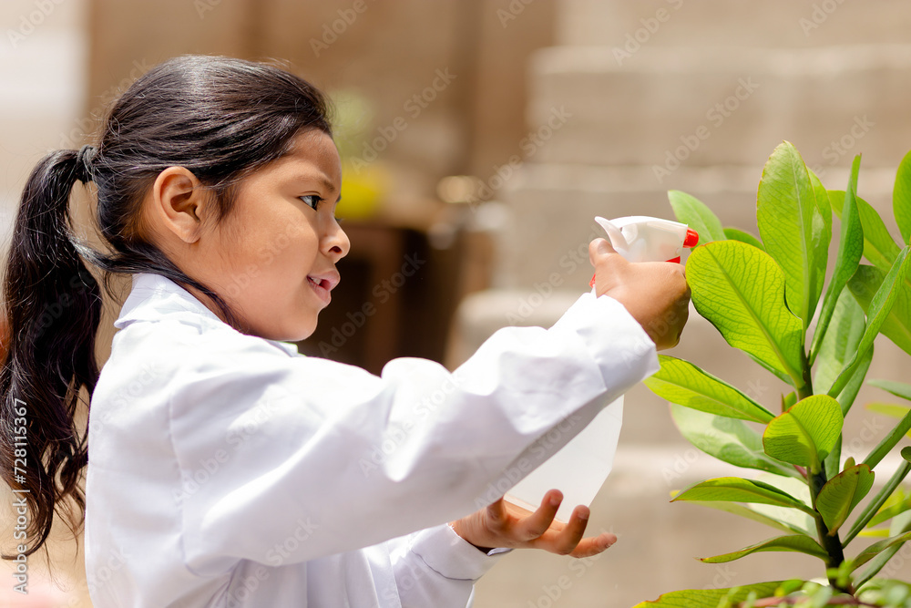 Little Latina girl in a white robe, watering and observing plants ...