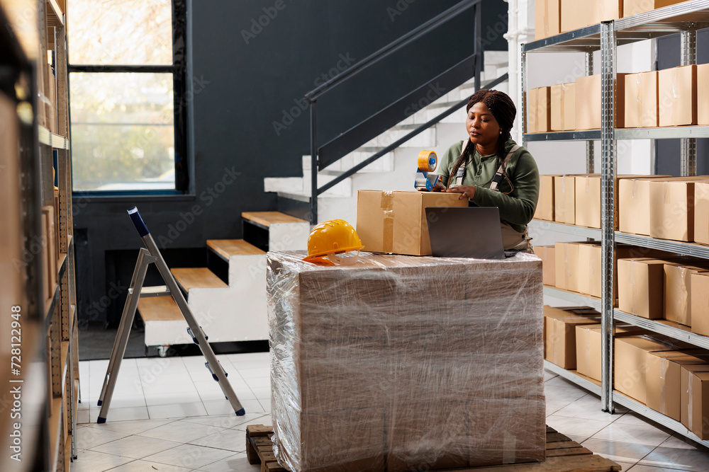 African american employee preparing clients orders, using adhesive tape ...