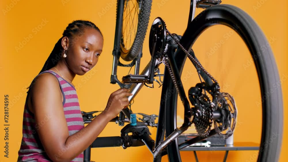 African american woman checking bicycle performance by spinning pedals ...