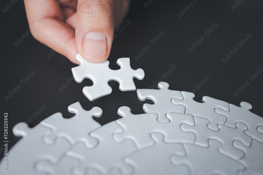 Hand put last piece of jigsaw puzzle. White unfinished jigsaw puzzle ...
