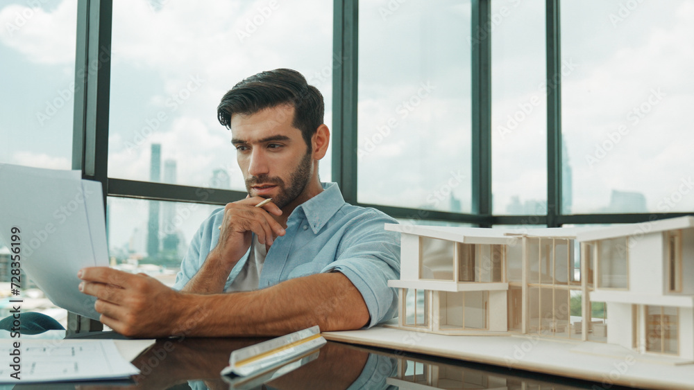 Portrait of smart skilled engineer checking house model while holding ...