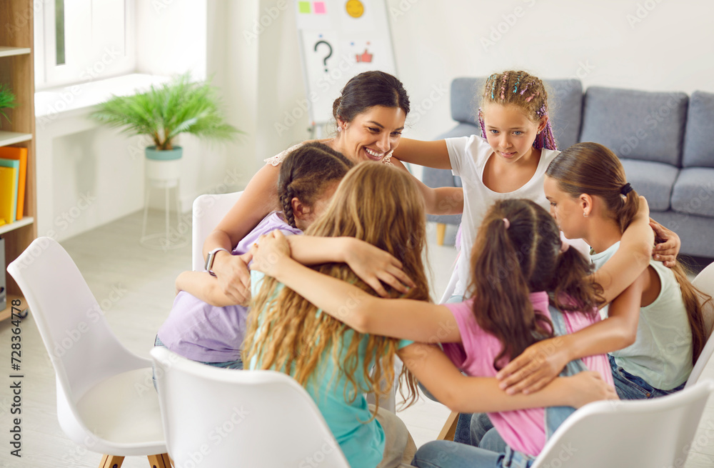 Teenage school girls sitting in a circle and hugging with their ...