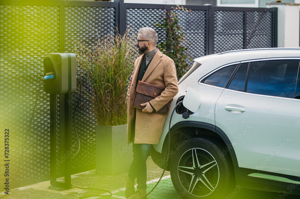 Businessman charging electric car before going to office. An electric ...
