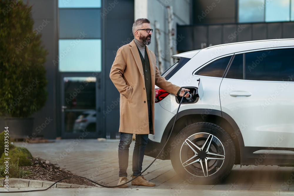 Businessman charging electric car before going to office. An electric ...