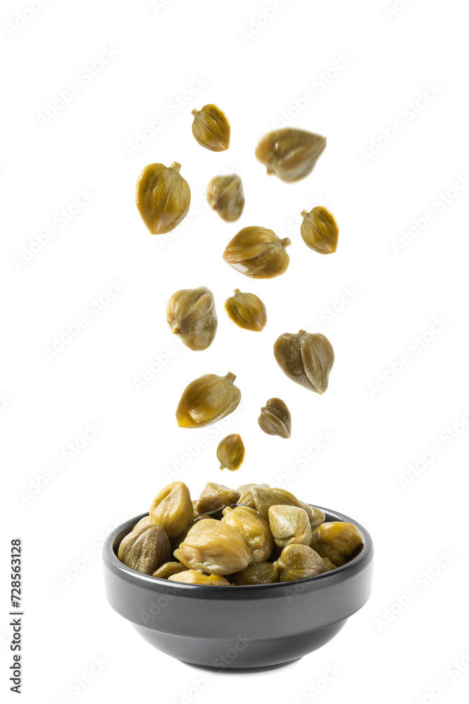 Pickled capers falling on a pile of capers close-up isolated on a white ...