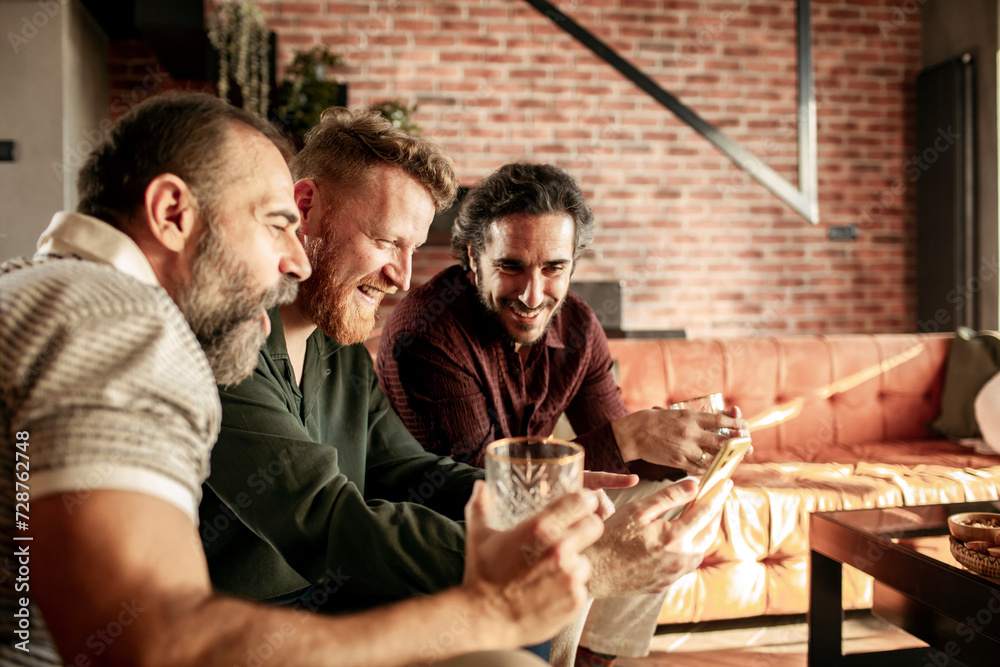 Group of men laughing and having drinks in a modern living room Stock ...