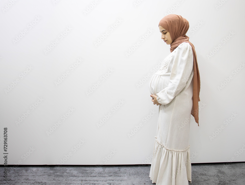 pregnant Arabic muslim female on isolated white background touching her ...