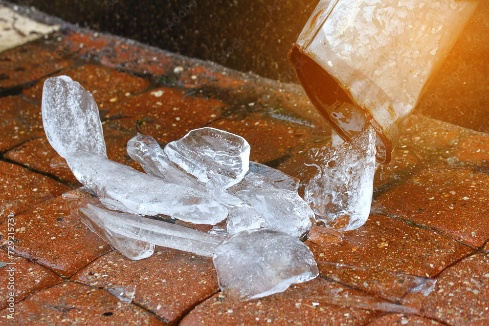 Drain pipe and melting ice, wet sidewalk. Ice in drainpipe, icy dam ...