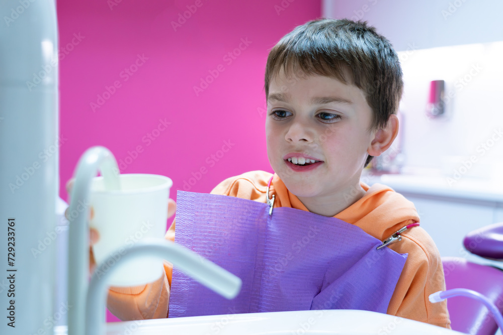 Boy at the dentist's office refilling a glass of water to rinse after ...