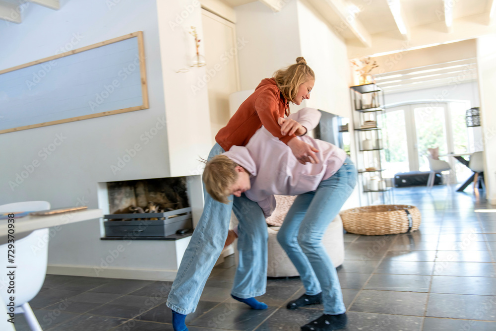 Brother and sister play fighting in their modern living room bright and ...
