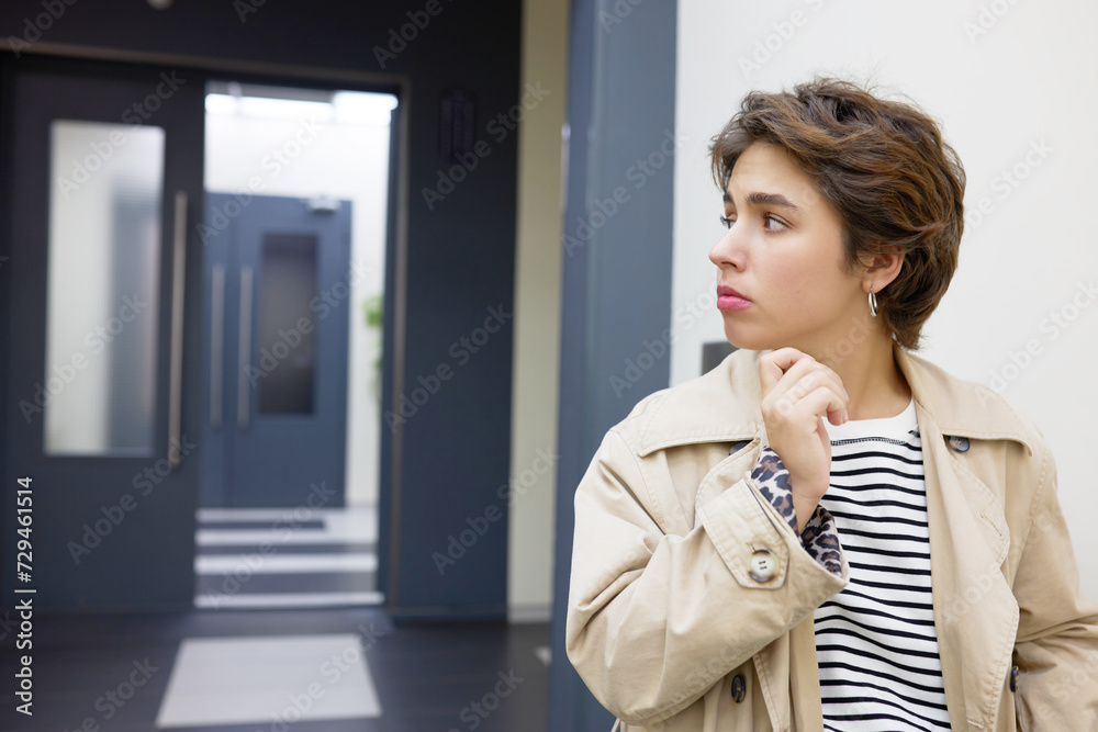 Scared worried anxious female standing in corridor of multi-storey ...