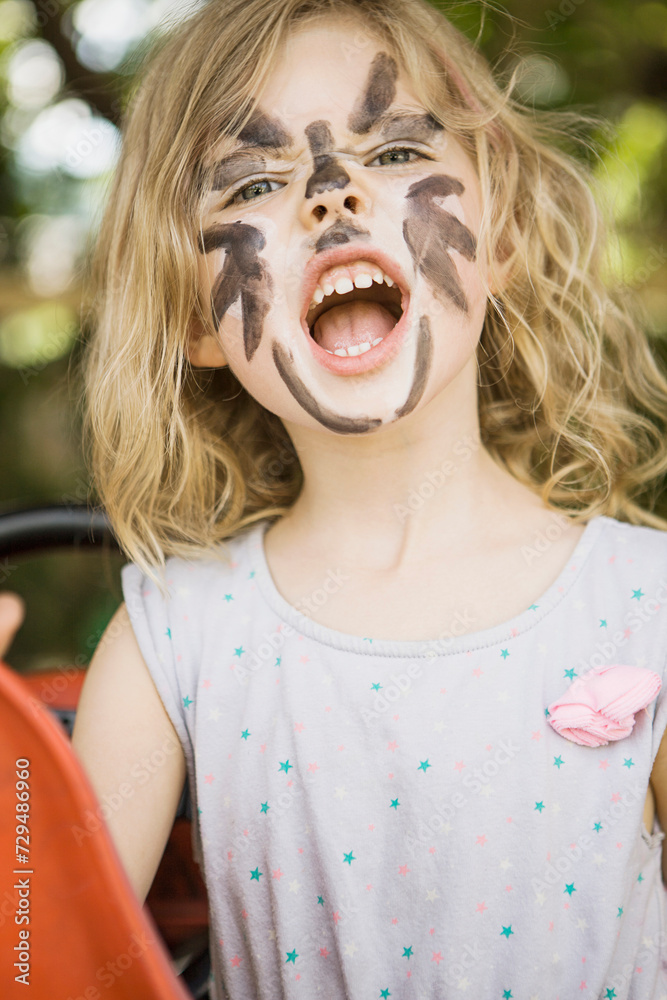 Young girl with painted face growling into the camera during carnival ...