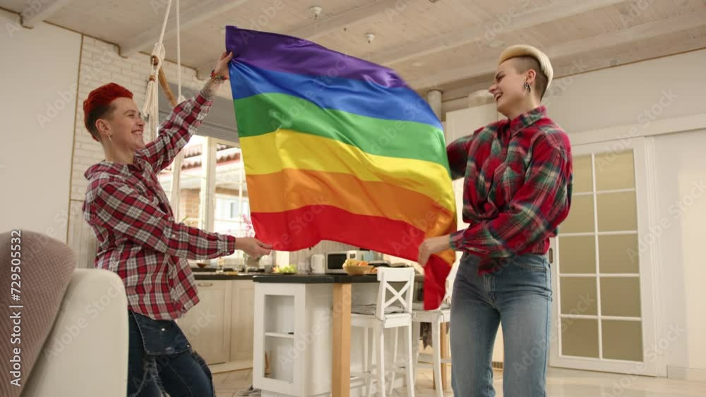 Two women in plaid shirts dance joyfully in their kitchen, waving a ...