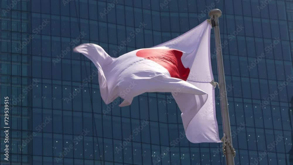Slowmotion of a Japanese flag waving in a modern skyscraper city ...