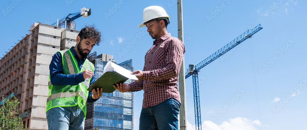 Workers at work signing some documents for a deal in construction site ...